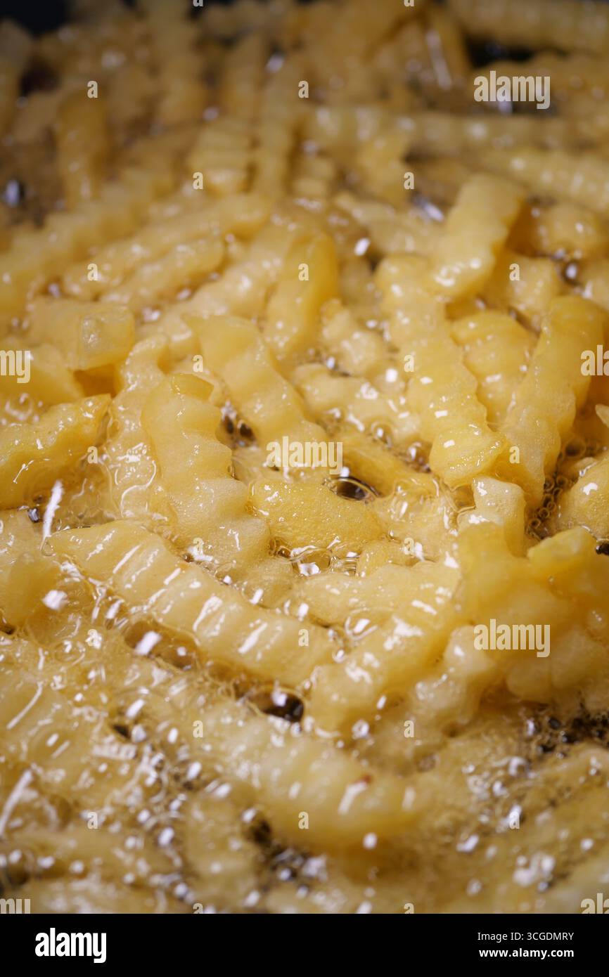 Frying crispy crinkle-cut potatoes in hot oil Stock Photo - Alamy