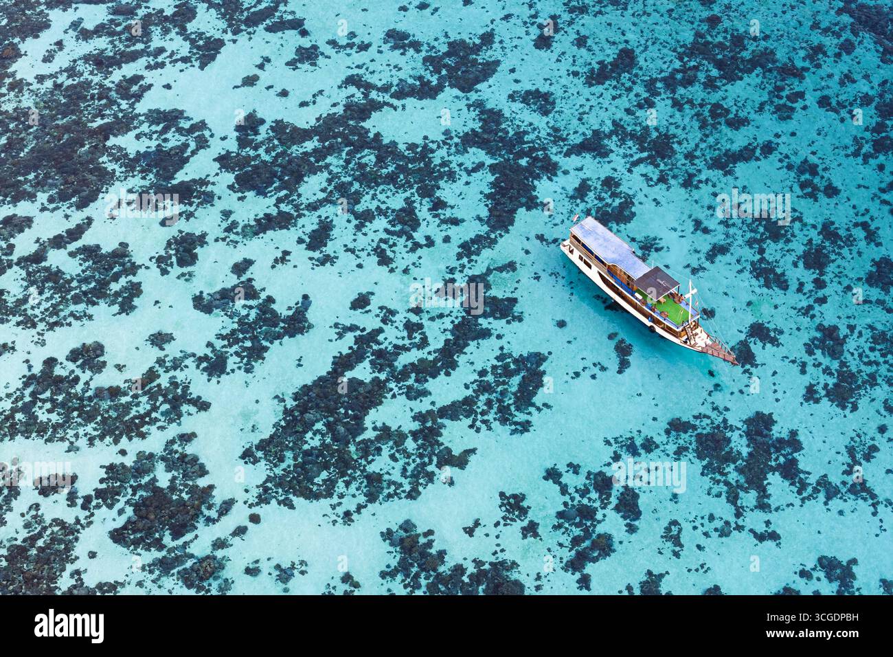 Aerial view of a boat sailing through the crystal-clear turquoise ...