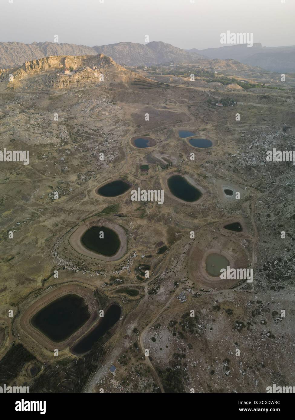 Aerial view of still, dark pools of water punctuate the arid landscape ...