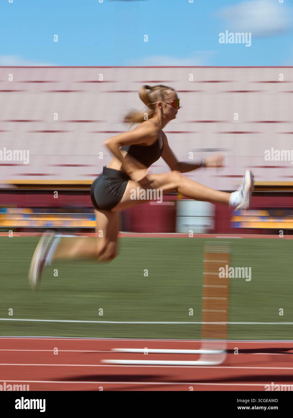 Female hurdler in fast motion blur over hurdle on track Stock Photo - Alamy