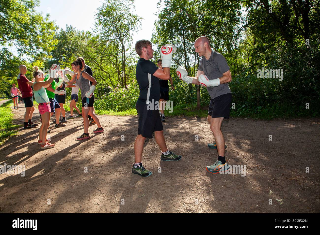 Outdoor group exercise class, boxfit in the park, male and female ...