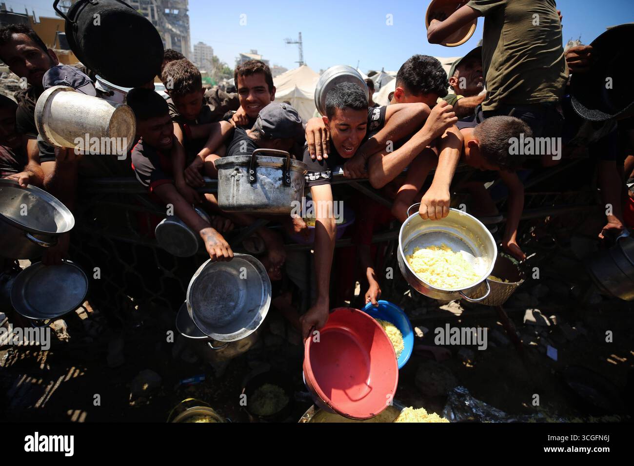 Palestinians wait to receive food from a charity kitchen Palestinians ...