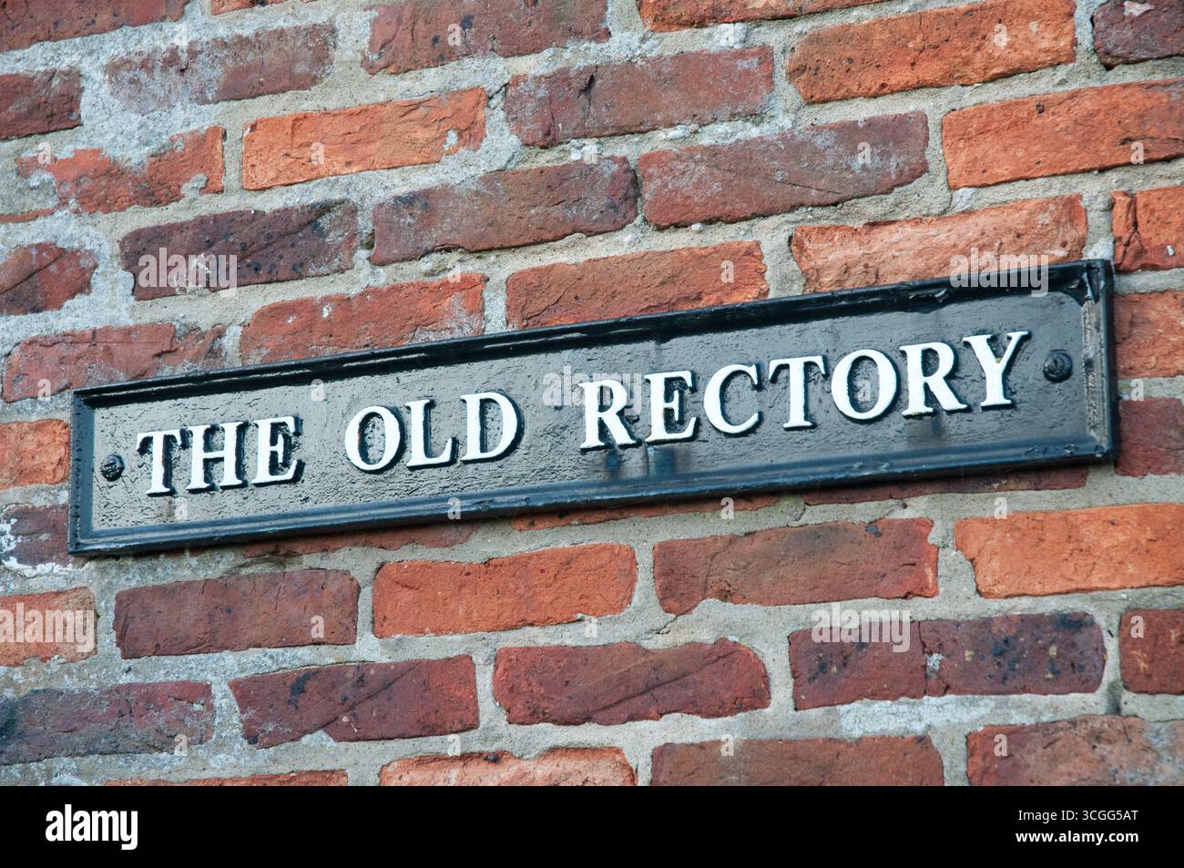A black and white sign reading Old Rectory is mounted on a rustic brick ...
