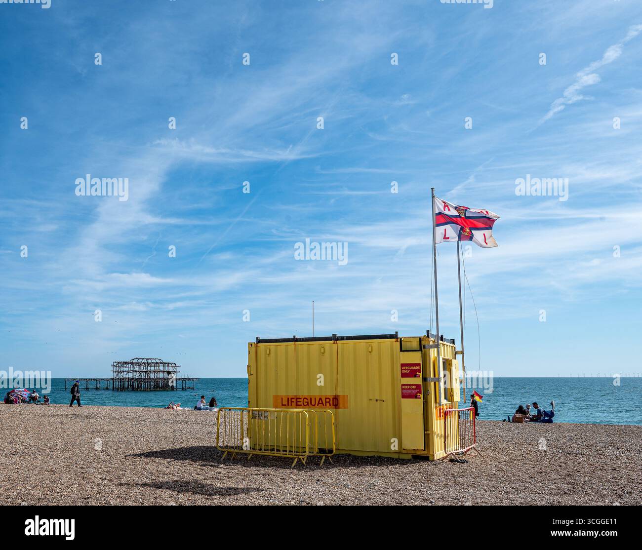 Yellow lifeguard hut displaying an RNLI flat on Brighton beach with the ...