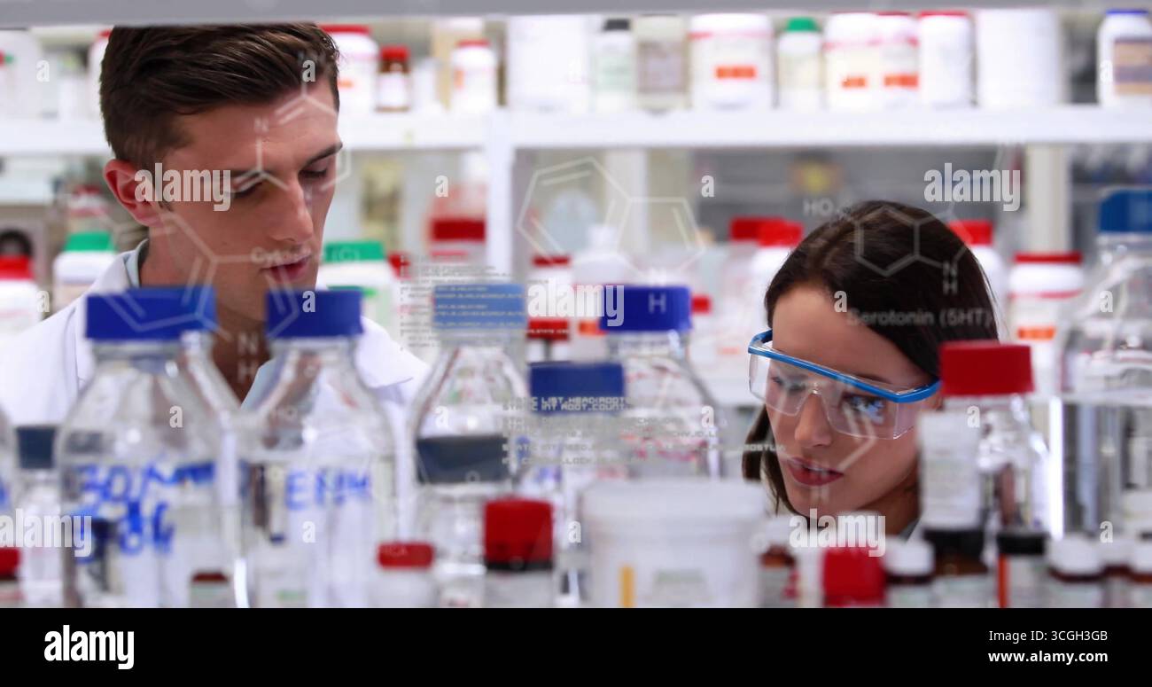 Two scientists in lab coats leaning over lab bench analyzing samples ...