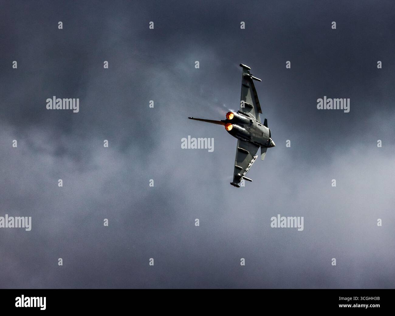 Jet fighter in a dynamic vertical climb against a stormy sky with ...