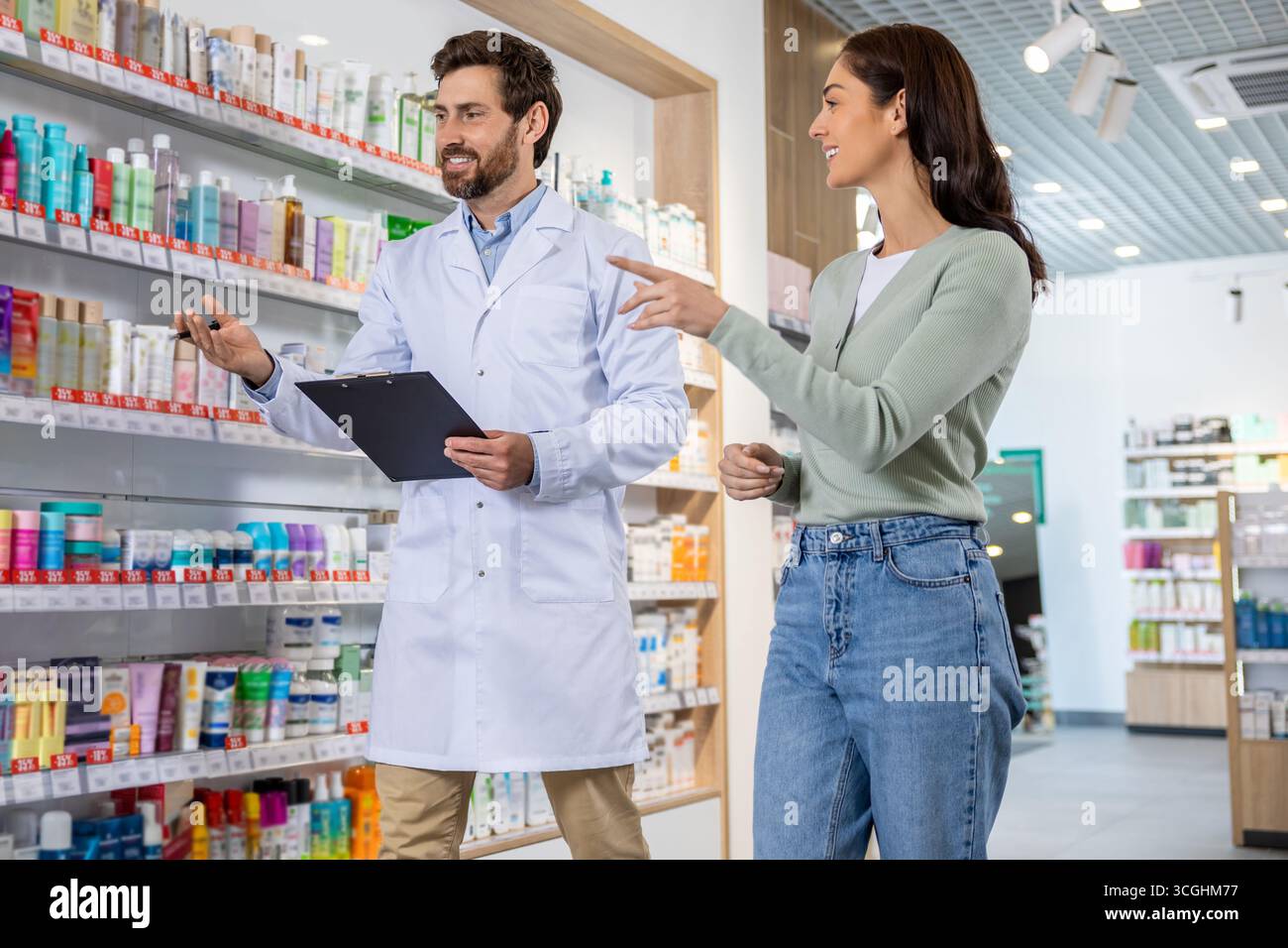 Male pharmacist talking to a woman and making notes Stock Photo - Alamy