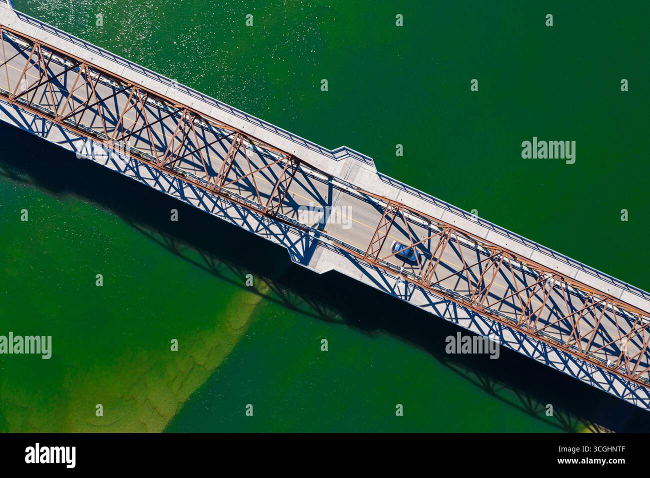 Bridge with a car on it. The bridge is green and the water is also ...