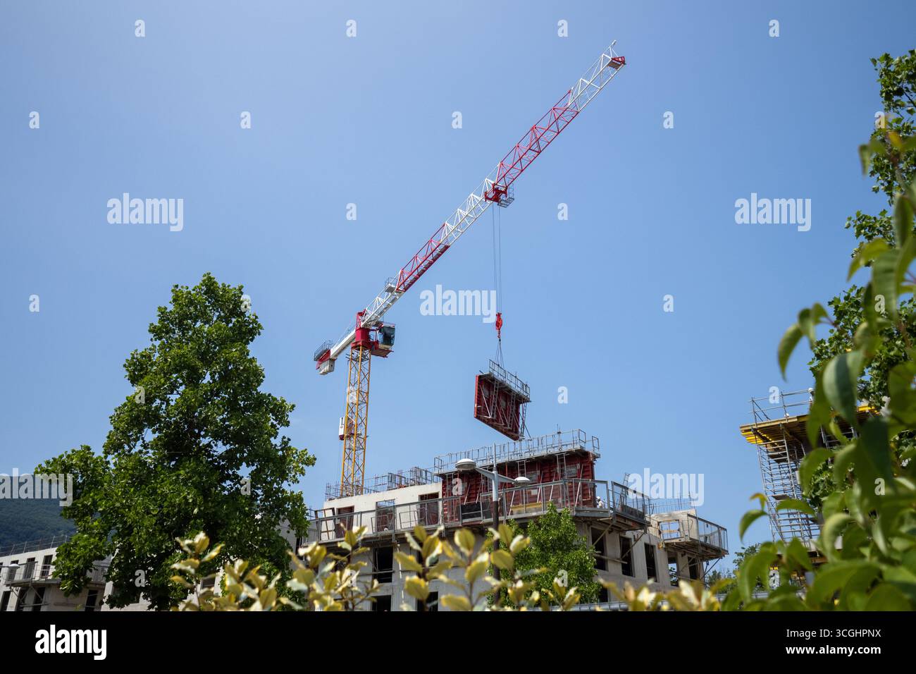 Construction crane lifting building materials on a construction site ...