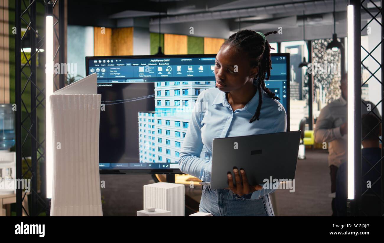 African american female evaluating 3D building model for measurements, creating construction ...