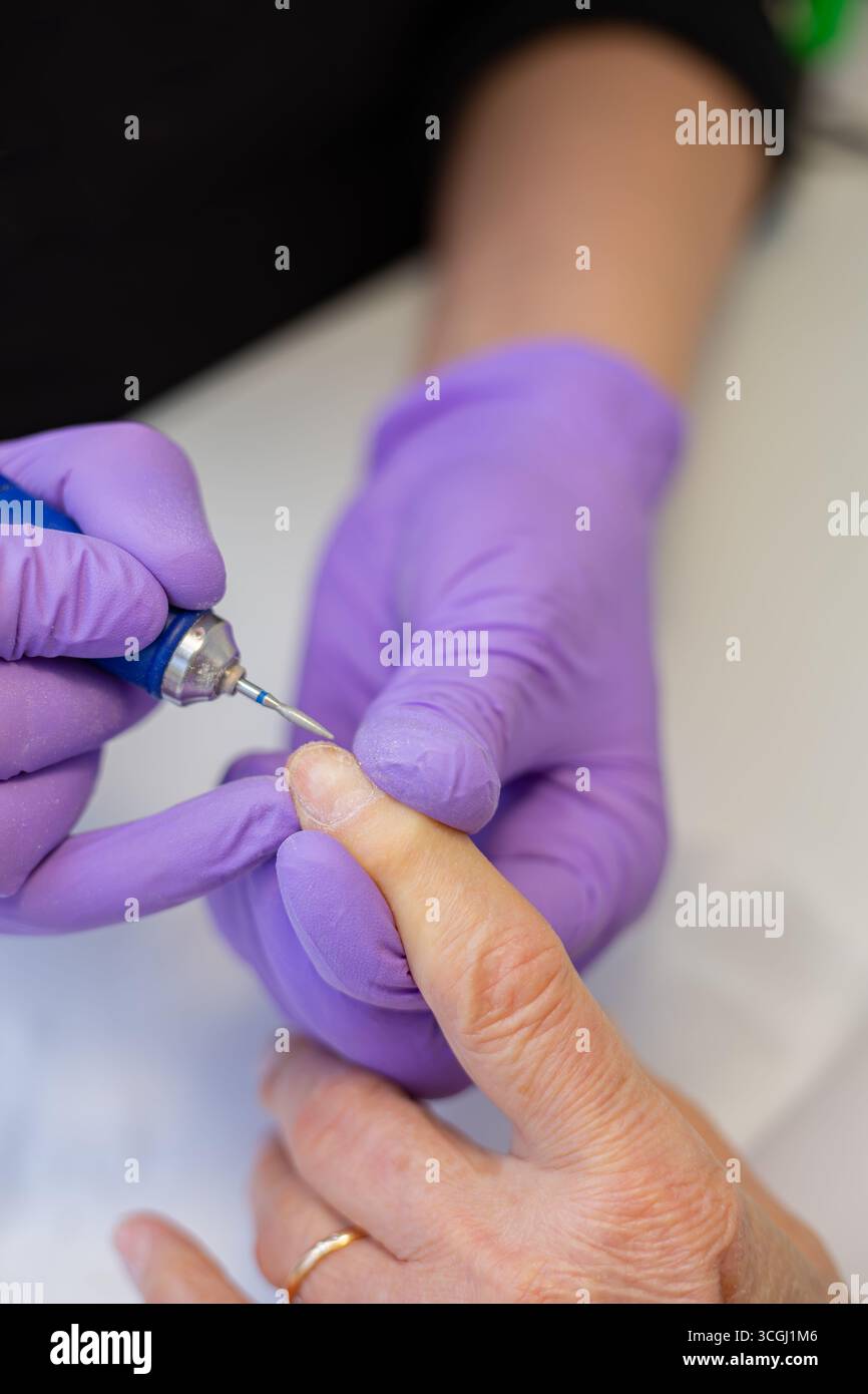 A beautician uses a modern professional electric manicure and pedicure ...