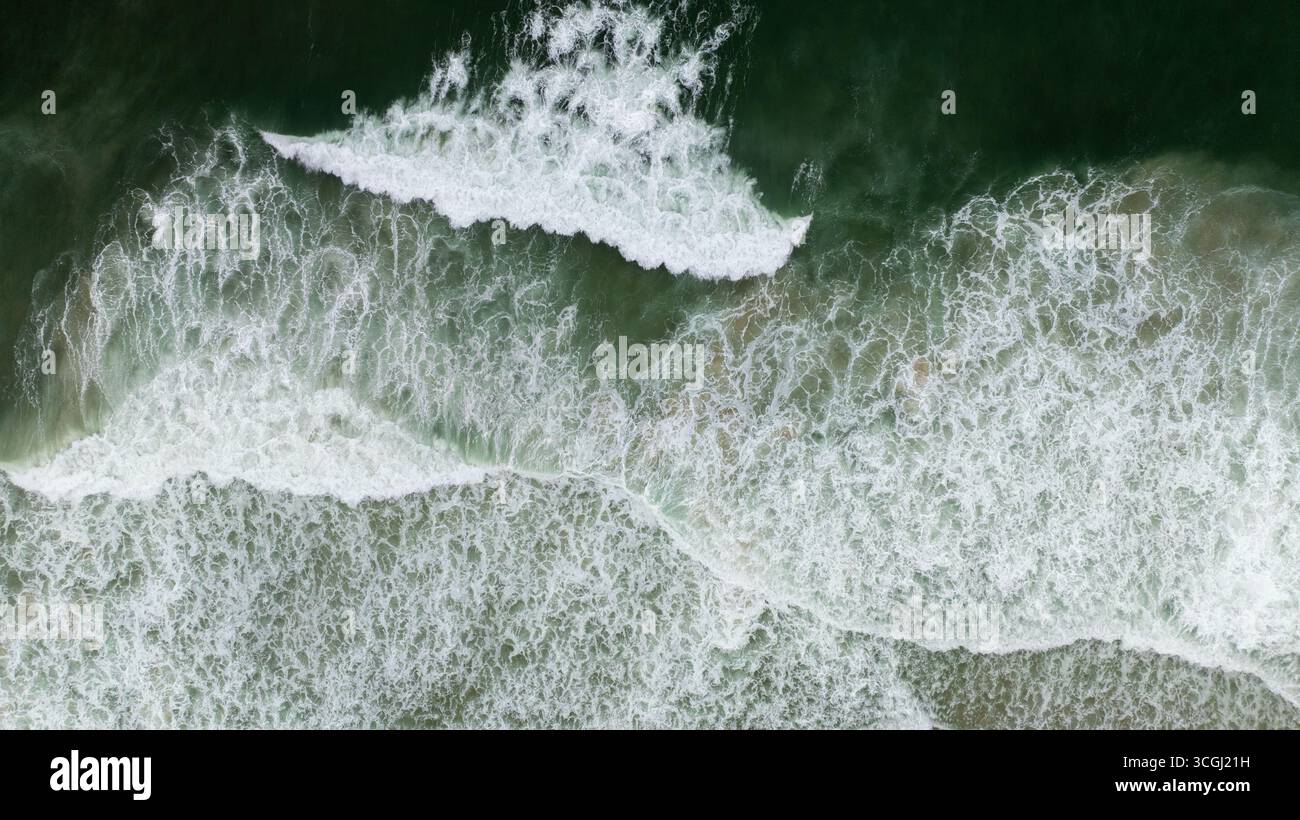 Aerial view of powerful ocean waves crashing on the shore, creating ...