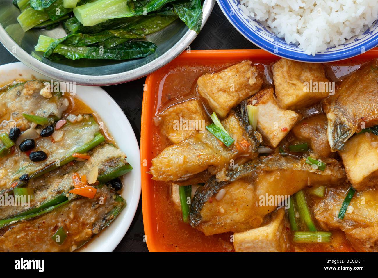 a colorful Asian meal featuring rice and braised fish with tofu and ...