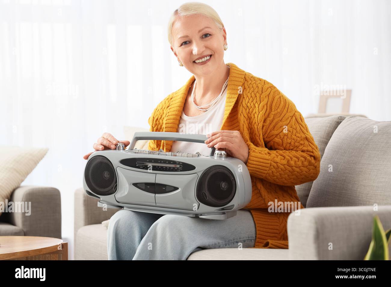 Senior woman with boombox sitting on sofa at home Stock Photo - Alamy