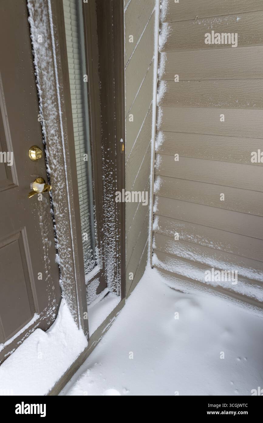 Partial view of a residential front door with snow drifting following a ...