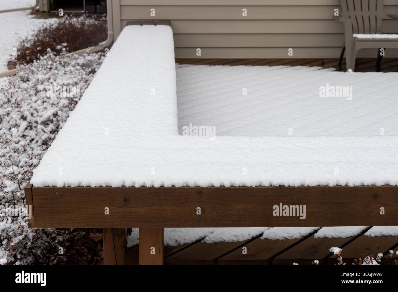 Backyard view of a snow frosted wooden deck bench following a late ...