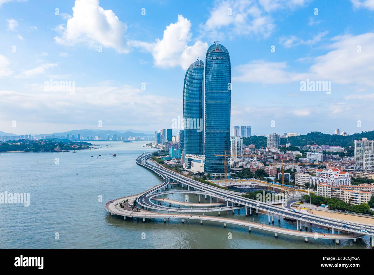 Tall blue towers rise above the city beside a wide blue water body ...