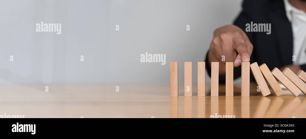 Close-up hand preventing falling domino wooden blocks on wooden table ...