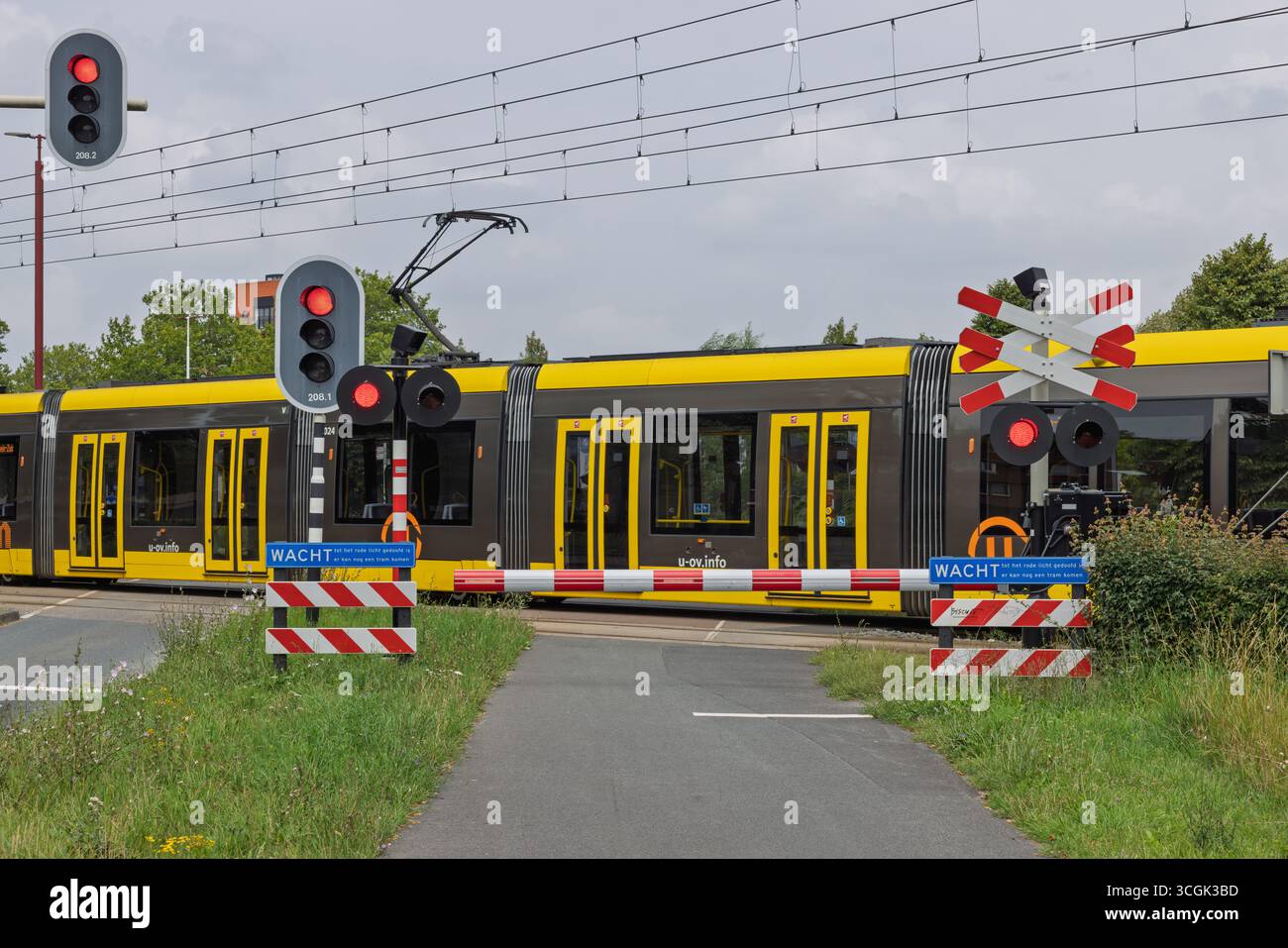 Modern light rail tram crossing a railway level crossing with warning ...