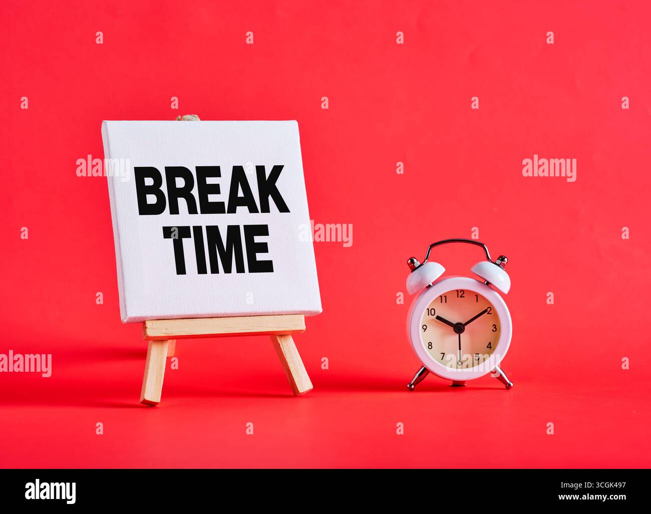 White alarm clock next to a break time sign on a red background ...