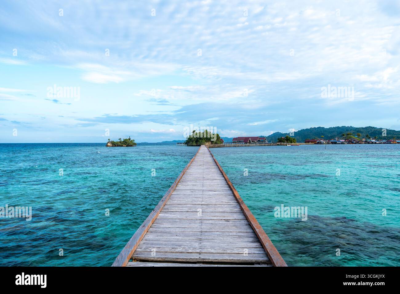 A long wooden jetty stretches over turquoise waters towards the ...