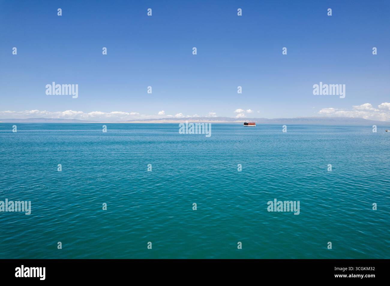 The vast turquoise waters of Qinghai Lake stretch under a clear blue ...