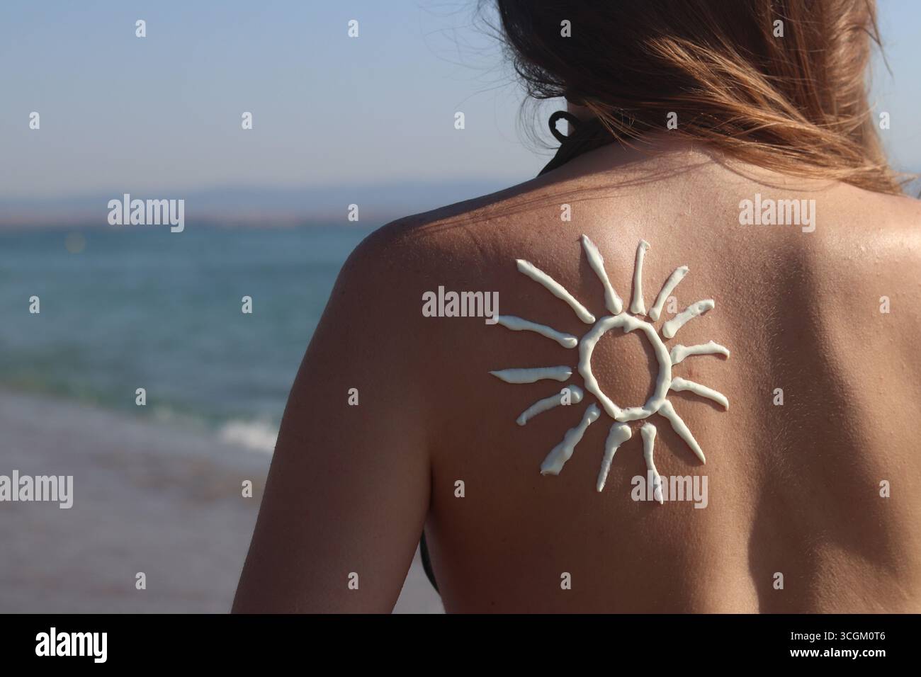 Sun image made with sunscreen on woman's back. Sunbathing on the beach ...