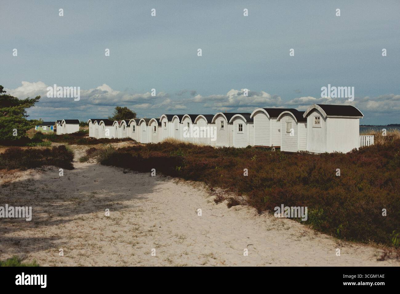 Several small, white beach huts infront of the sea at Höllviken ...