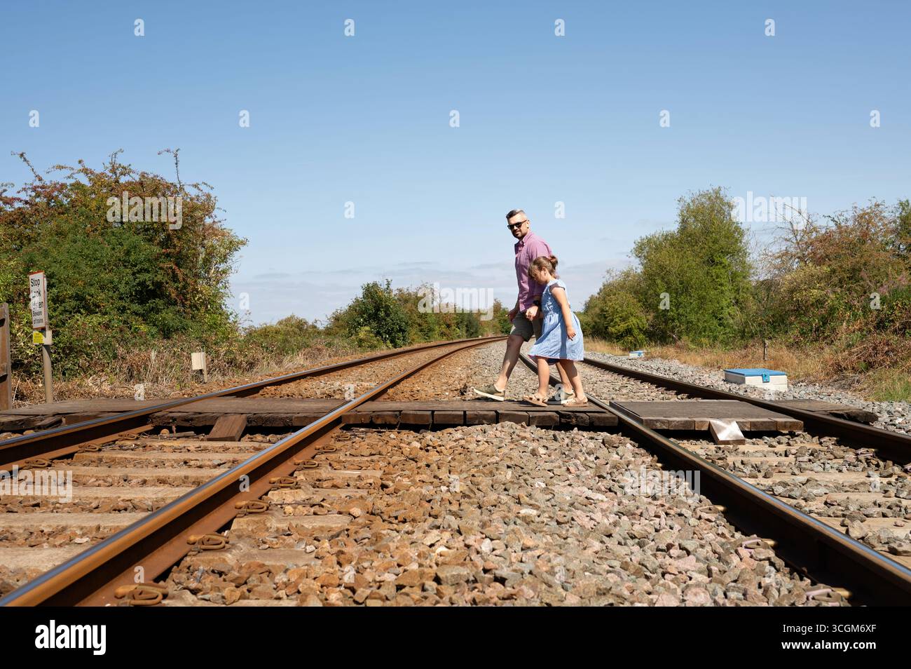 Father and daughter walking across level crossing, side view Stock ...