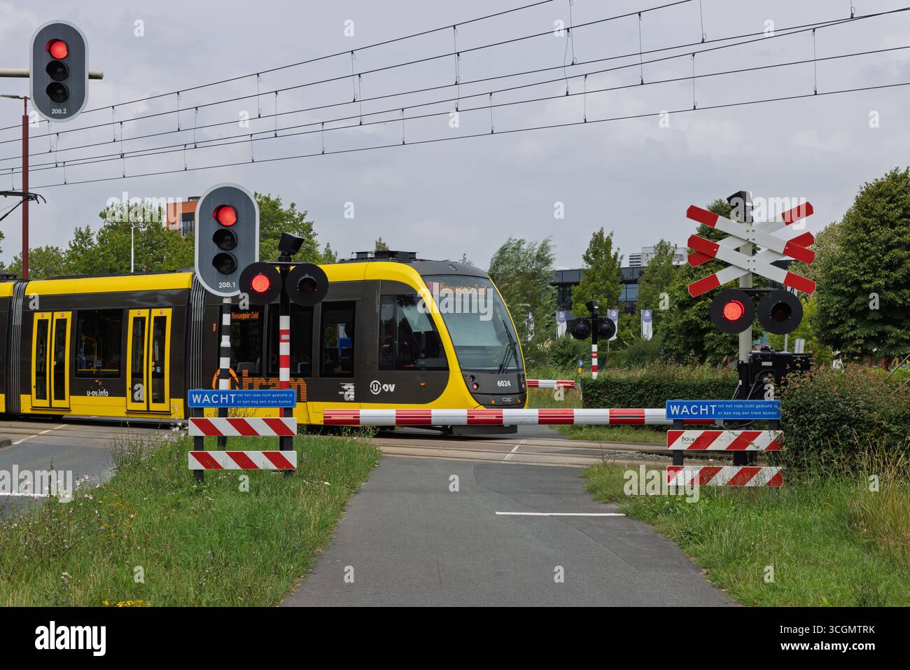 Modern light rail tram crossing a railway level crossing with warning ...