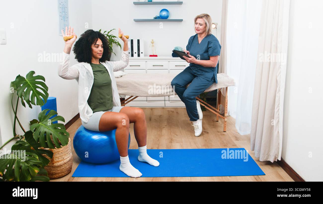 A Senior Physiotherapist Assists a Young Black Woman Client with ...