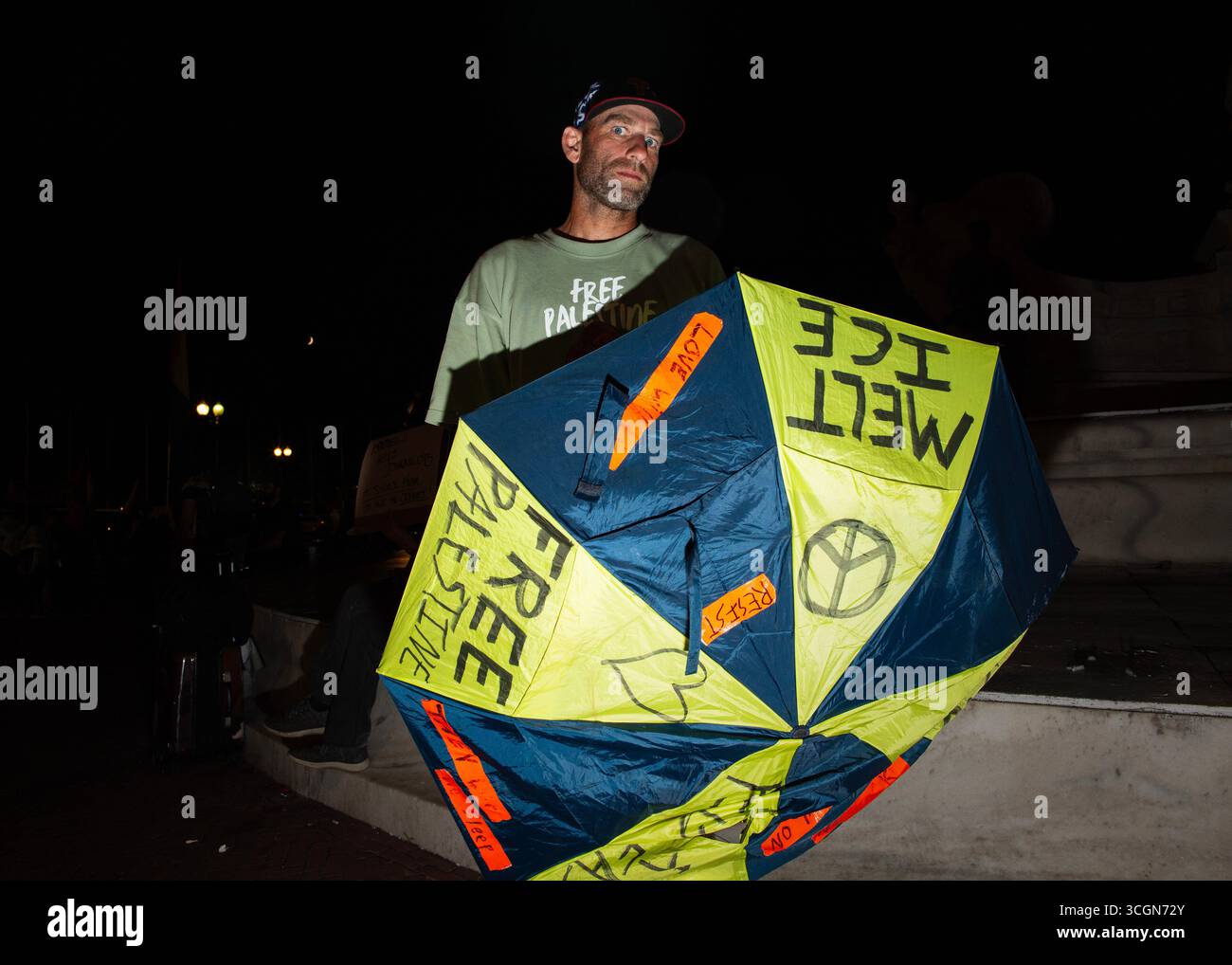 A person holds an umbrella that reads "Free Palestine, Melt ICE," joins ...