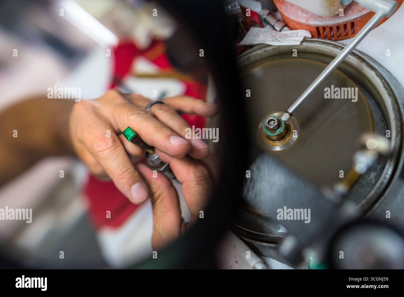 A Colombian gem cutter examines an emerald during the faceting process ...