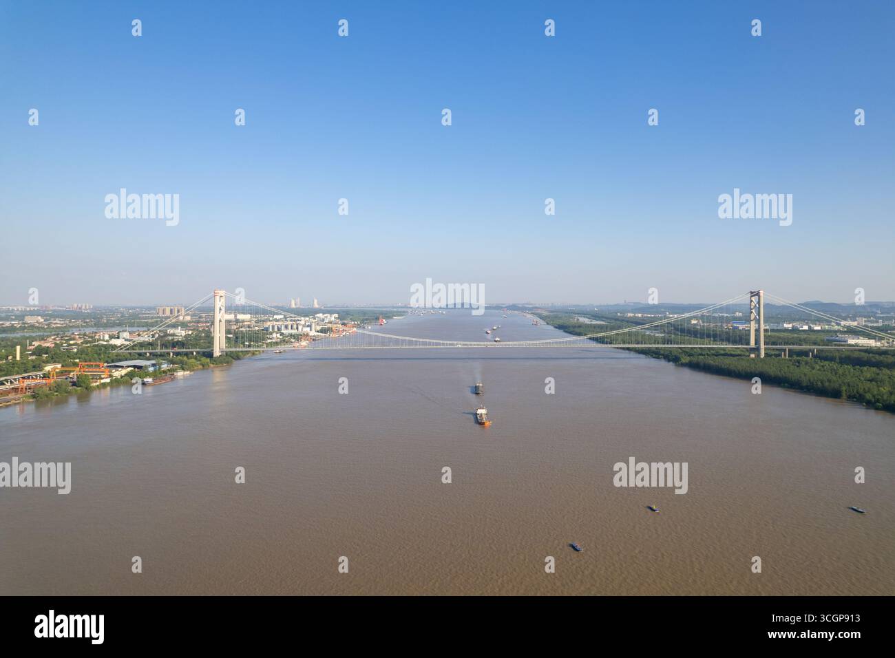 Large river with suspension bridges and boats seen from above in China ...
