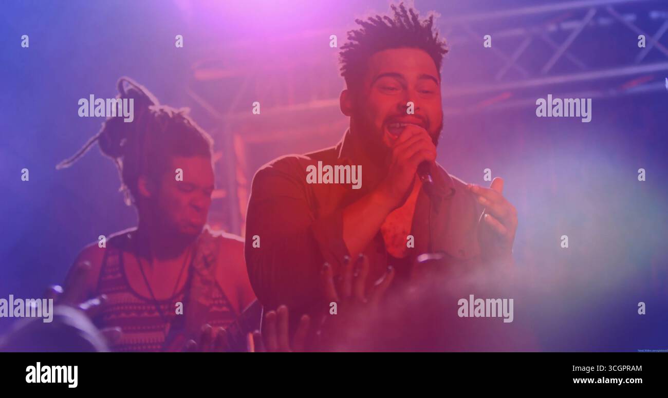 Performing mid adult singer gripping microphone, singing on concert ...