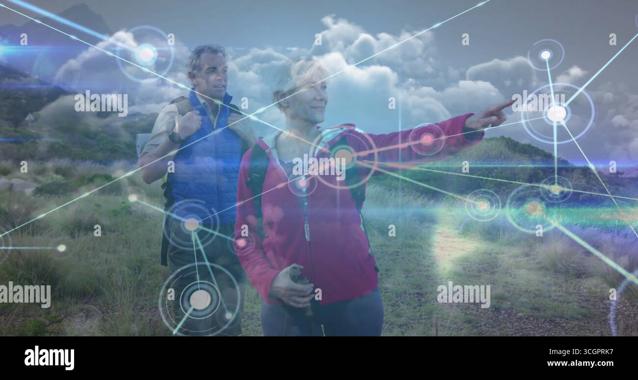 Pointing mature woman guiding hiking partner along trail, with trekking ...