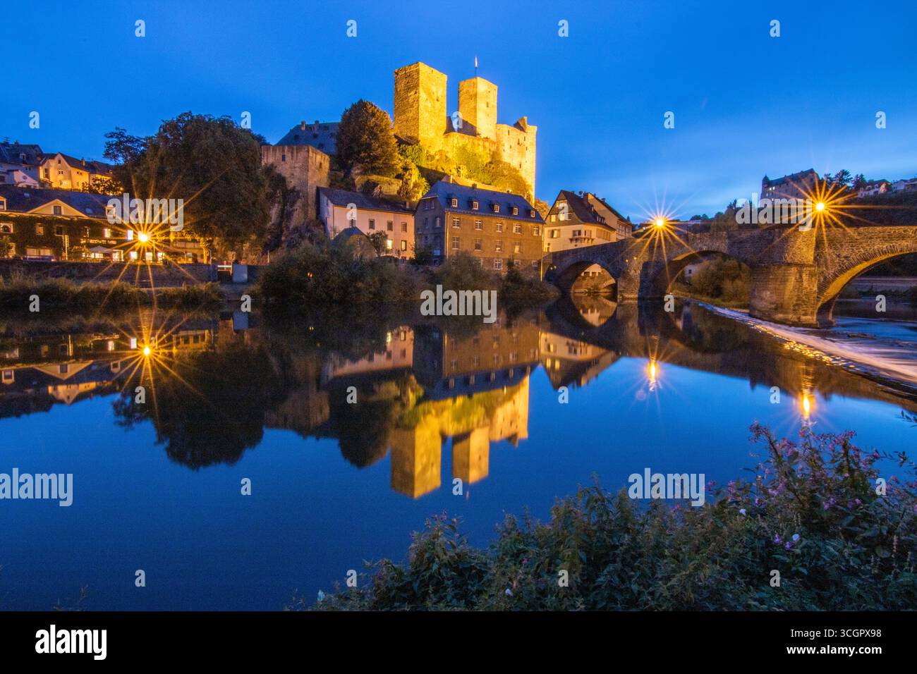 A town with a castle and a river. The historic center at night in a ...