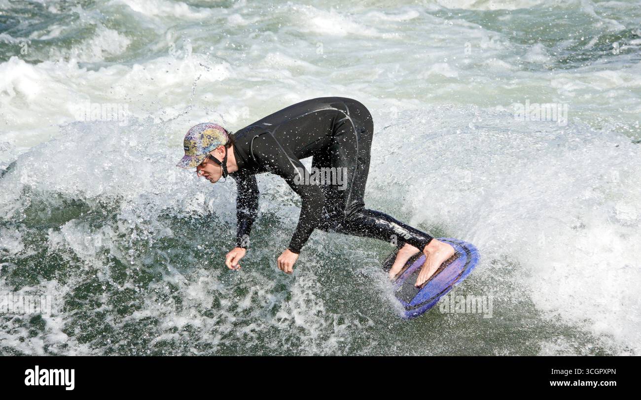 A man in a wetsuit rides a large wave while rivere surfing on the ...