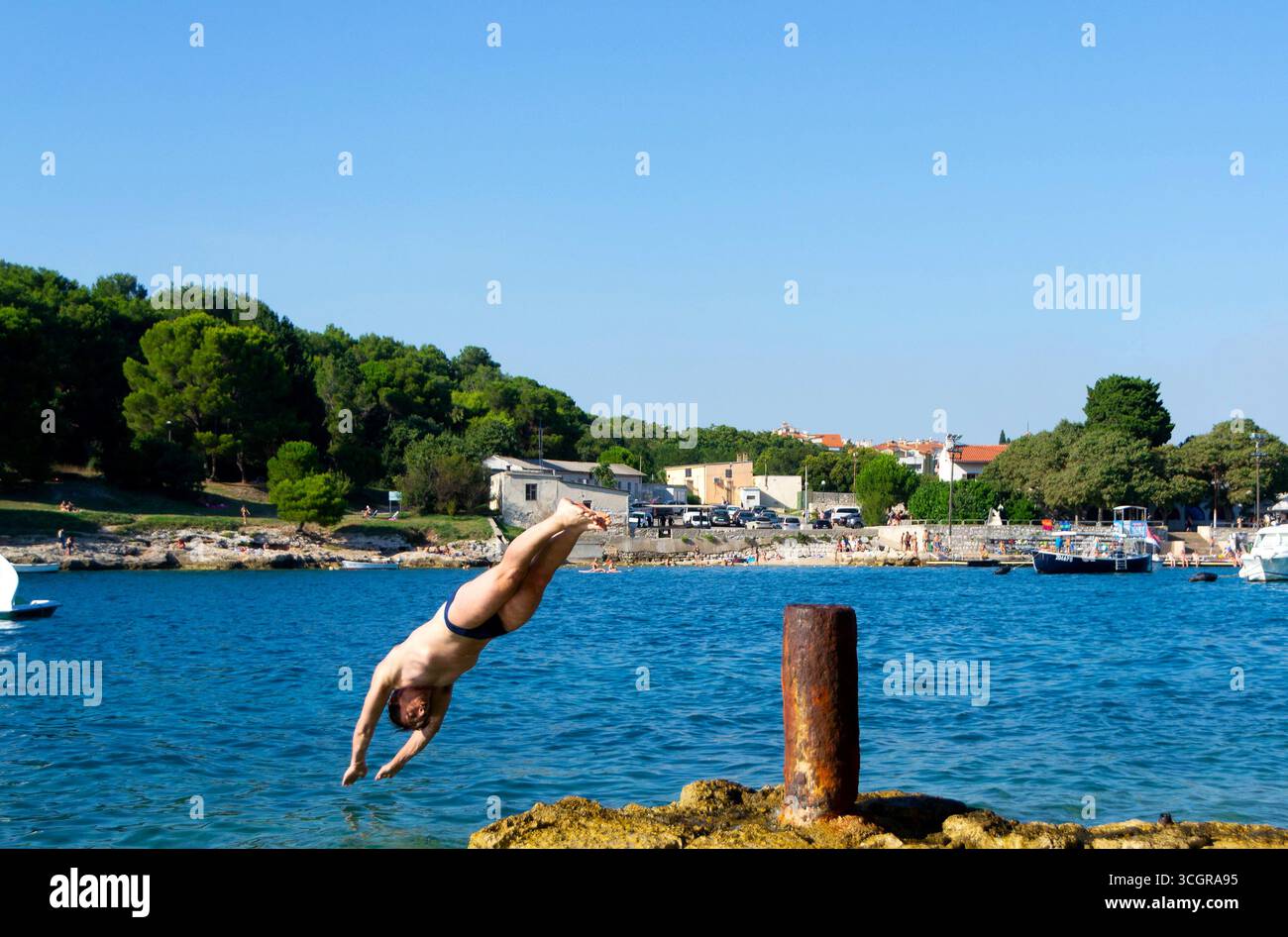 A man jumps from a metal dock bollard into the Adriatic Sea. Captured in sequence from standing ...