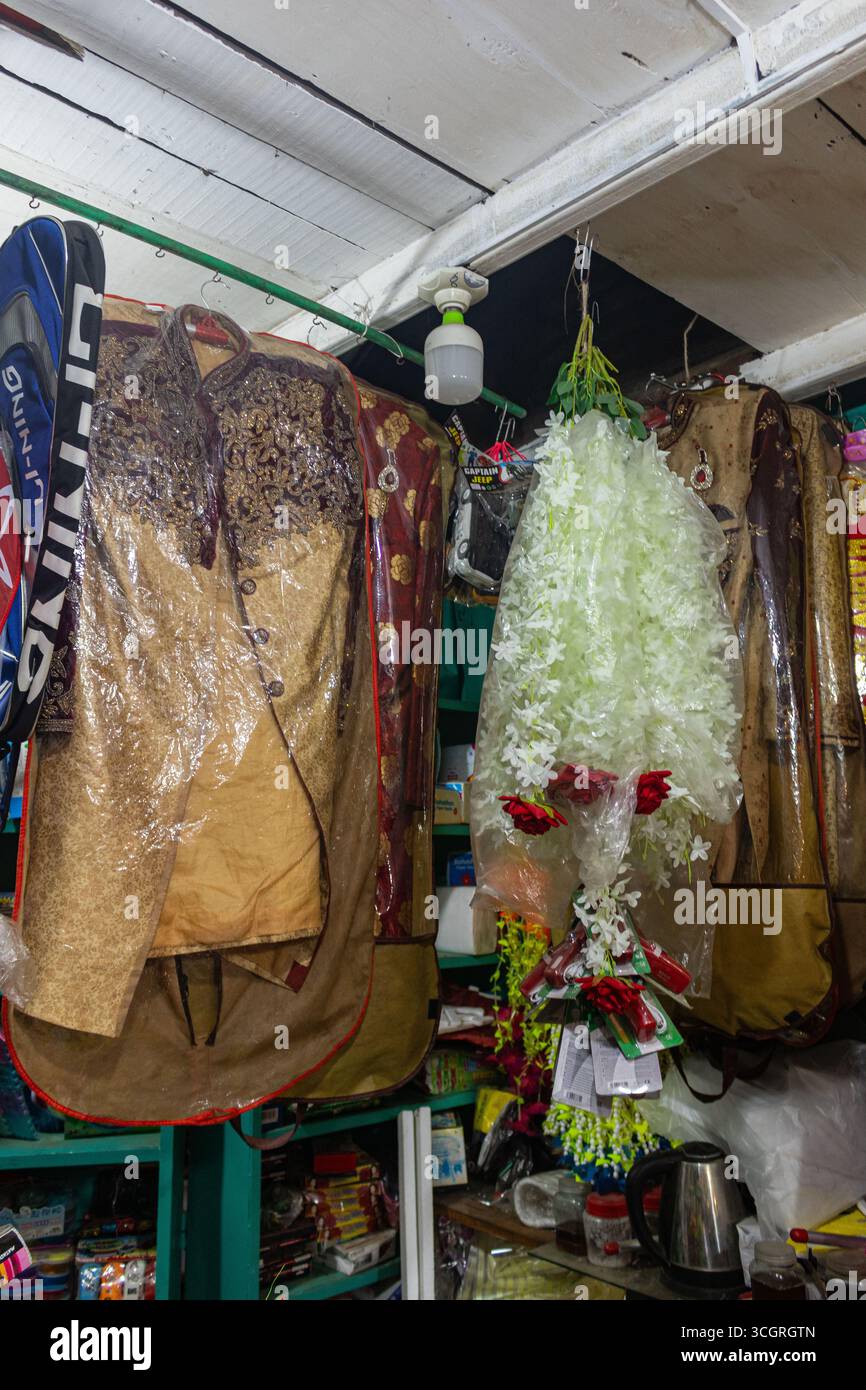 Elegant golden wedding sherwani with floral garland in shop display ...