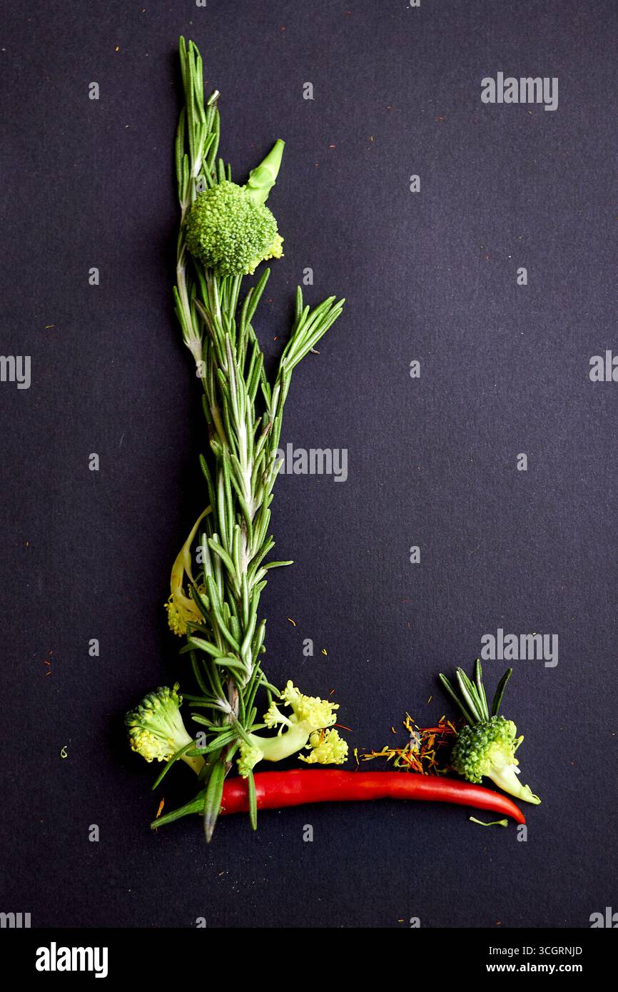 Creative letter L formed with rosemary, chili pepper, and broccoli on ...