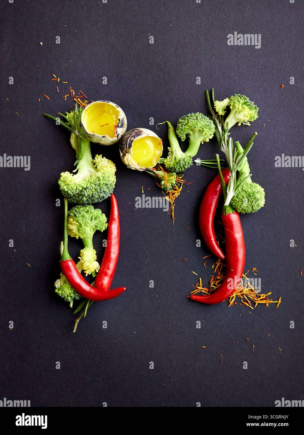 Creative letter M designed from chili peppers, broccoli, rosemary, and ...