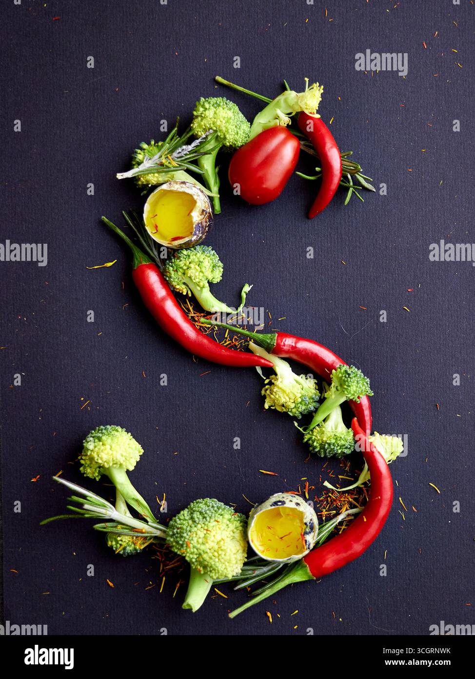 Creative letter S styled with chili peppers, broccoli, tomato, rosemary ...