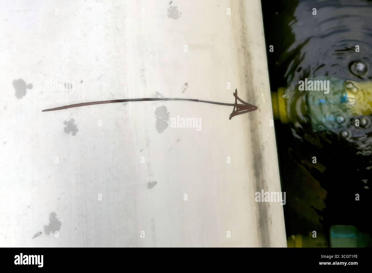 A clear arrow is marked on a metal pipe directing towards water below ...