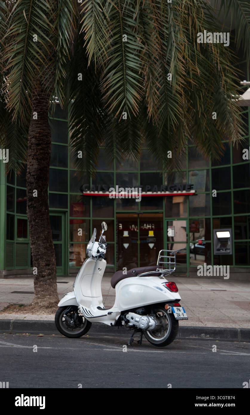 A white Vespa scooter parked in front of a bank with an ATM machine ...
