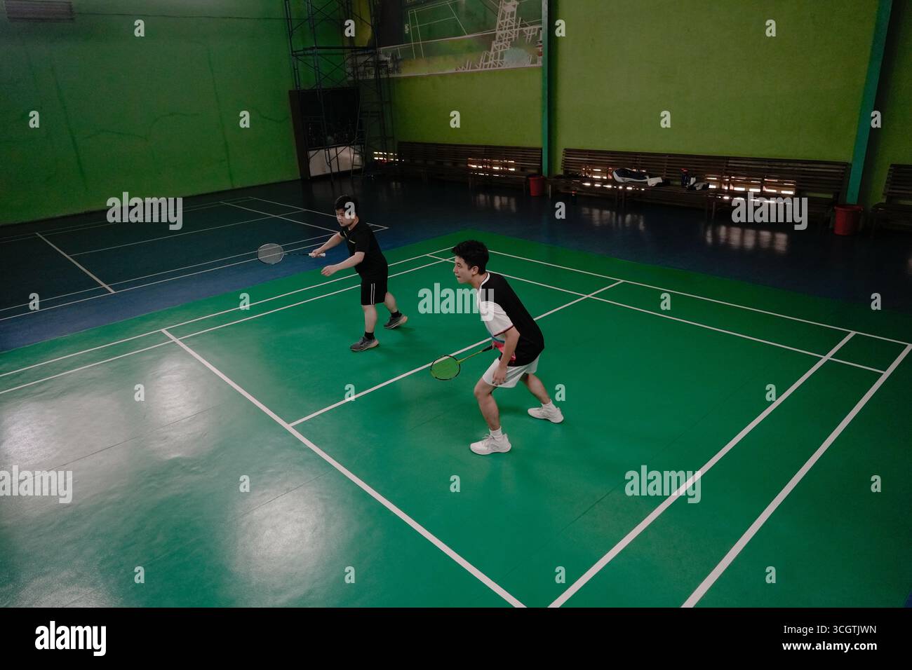 two players competing in a badminton match on an indoor court Stock ...