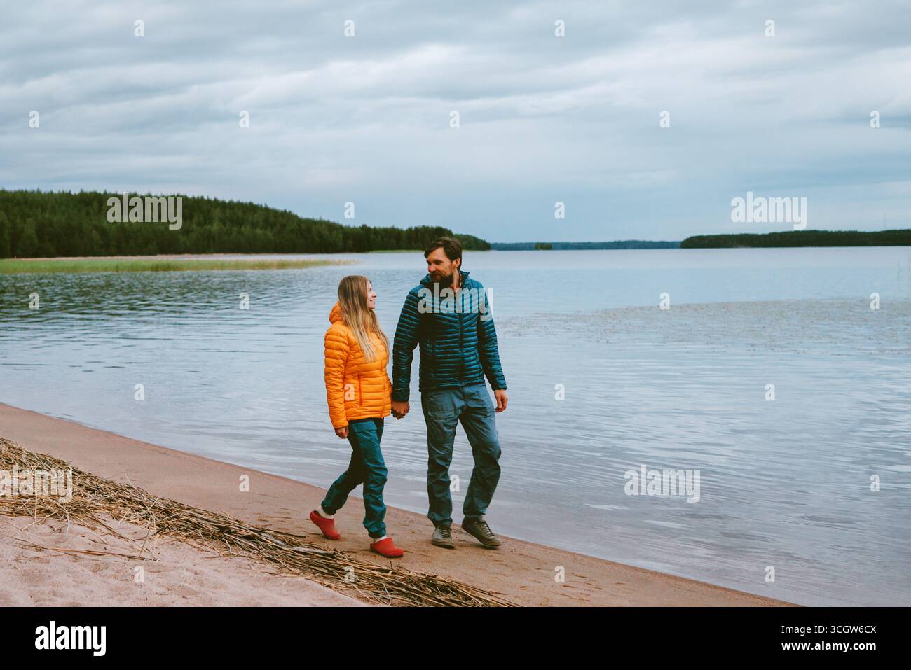 Romantic couple in love walking along lakeshore in Finland man and ...
