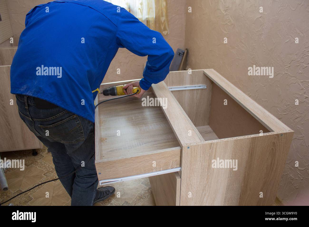 man gathers furniture with his back wrapped, assembling drawers ...