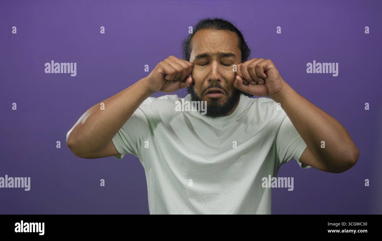 Man rubbing cheek and squinting with hand to face, bearded in a studio ...