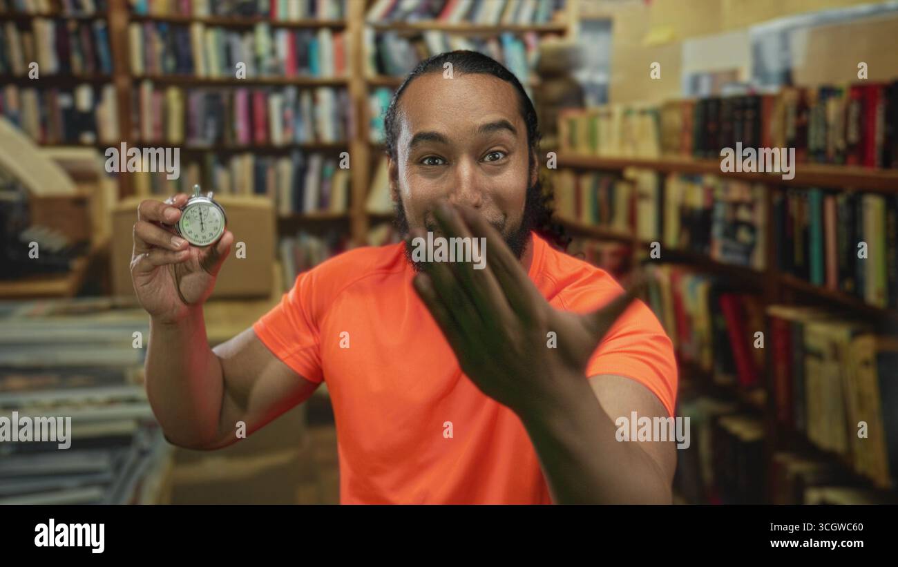 Man holds stopwatch and reaches hand forward in library building while ...